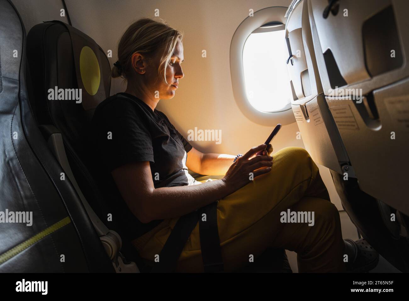 Passenger woman is flying in plane. Girl using phone sitting by ...