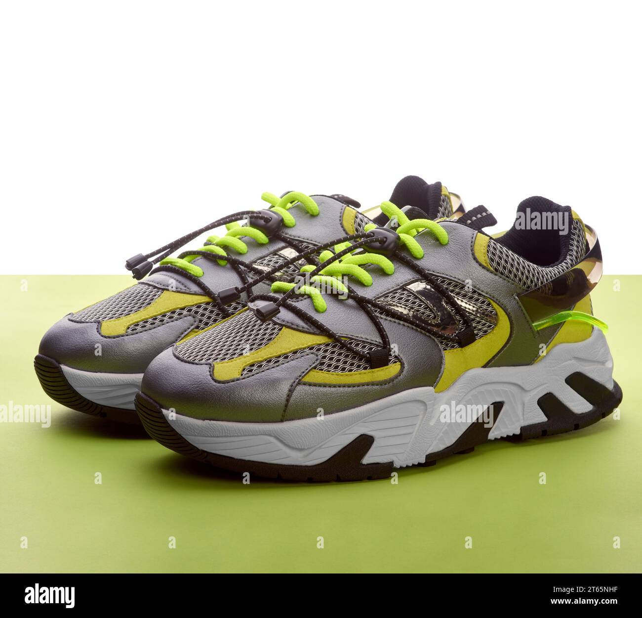 Female fashionable metallic grey running shoes with bright green laces ...