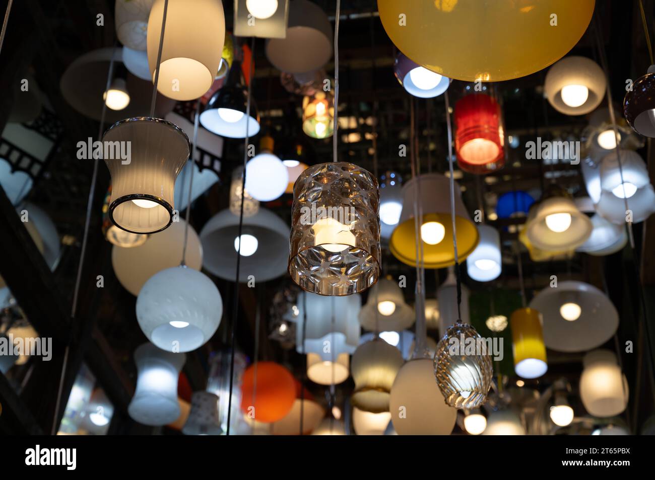 Many different ceiling lamps with lightbulbs in dark room with wall ...