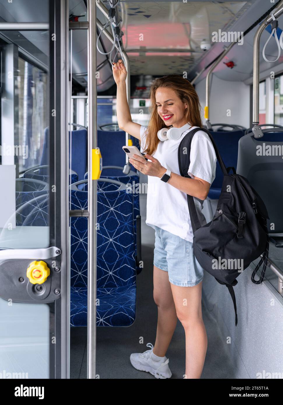 Young urban woman stands inside the bus and uses her mobile phone ...