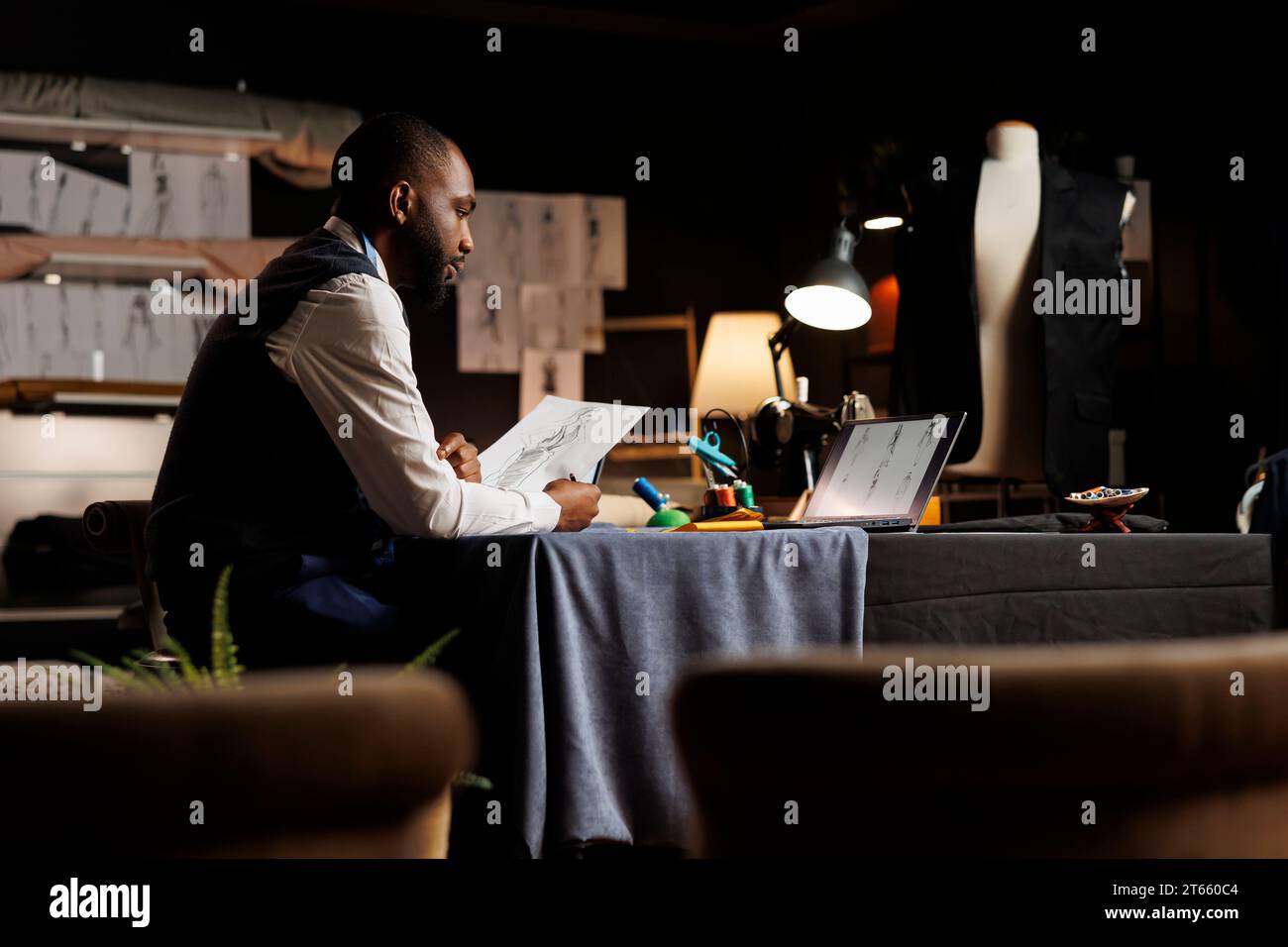 Hip level shot of skilled dressmaker in atelier shop workspace ...