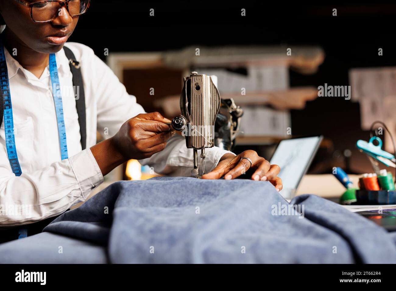 Close up of african american couturier using industrial sewing machine ...