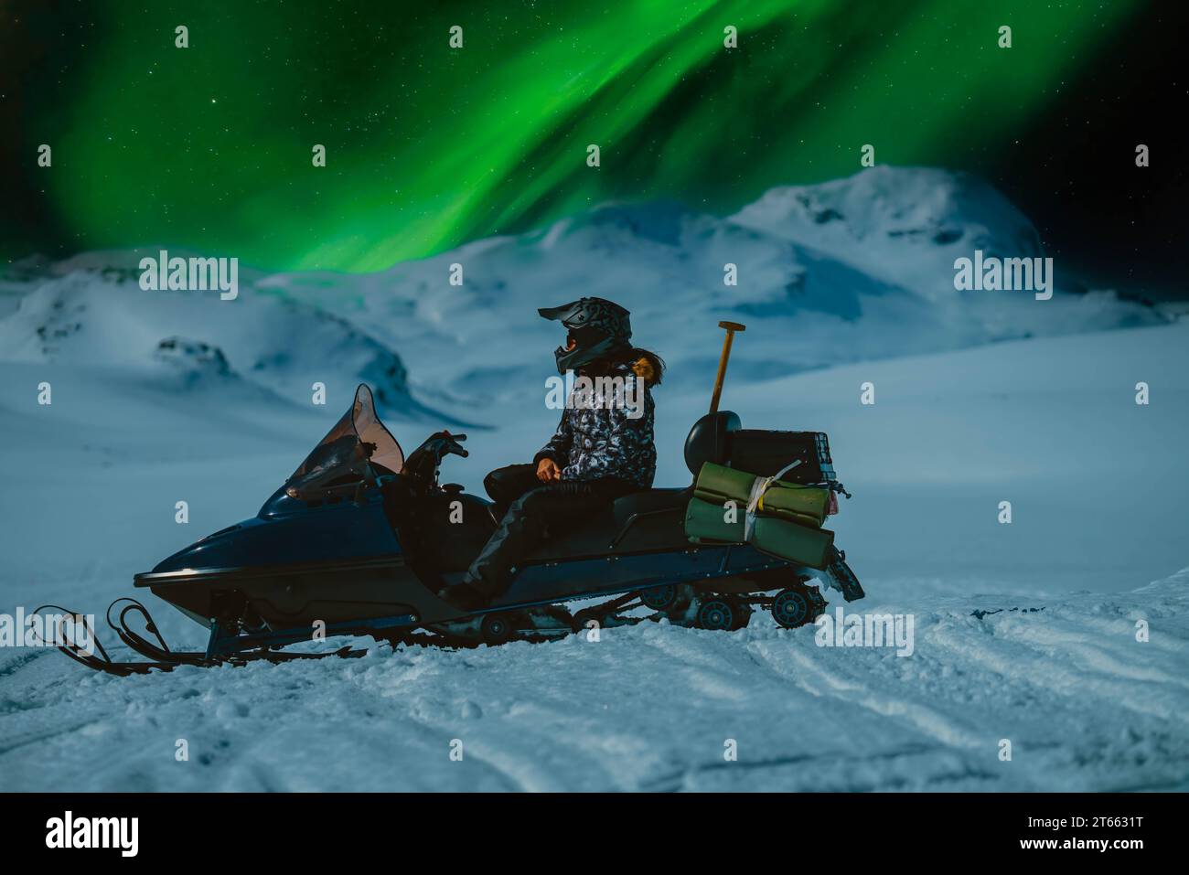 Scenic close up side photo of girl sitting on snow mobile with night ...