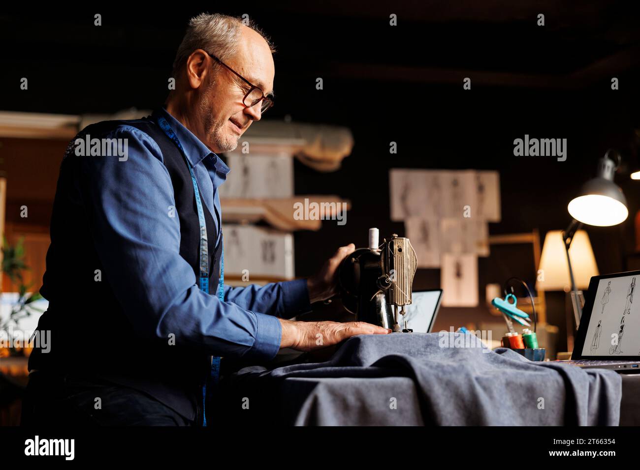 Elderly couturier cutting fabric material with professional sewing ...