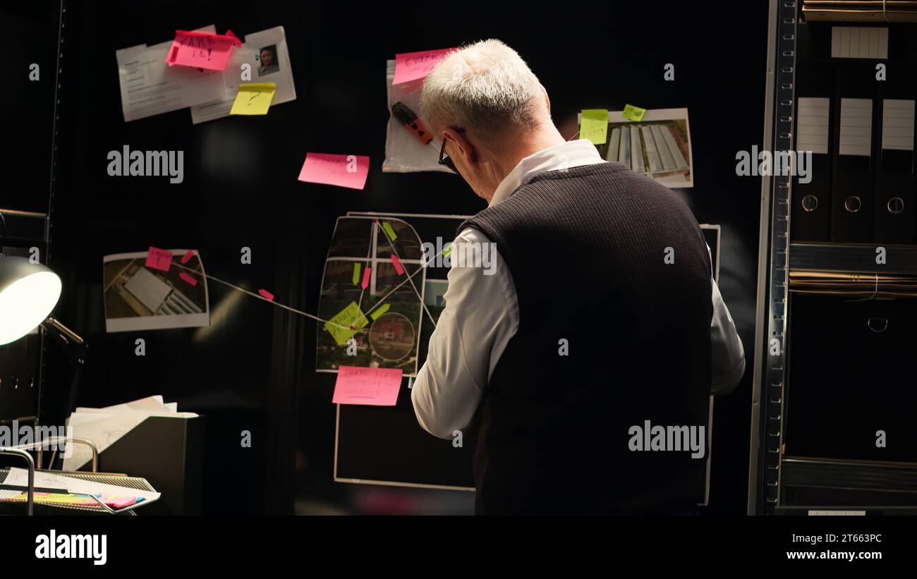 Senior detective analyzes clues board in evidence room, looking at ...