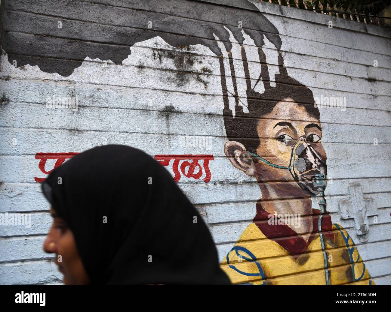 A woman walks past a mural painted on the wall to create awareness ...