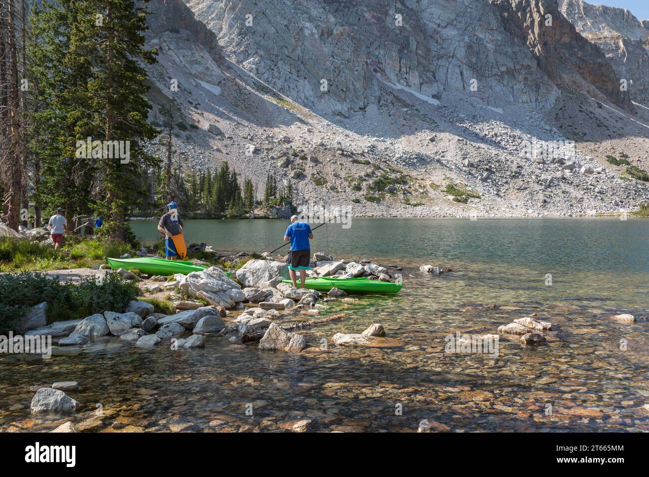 Two young men prepare for kayaking along the rock shoreline of Lake ...