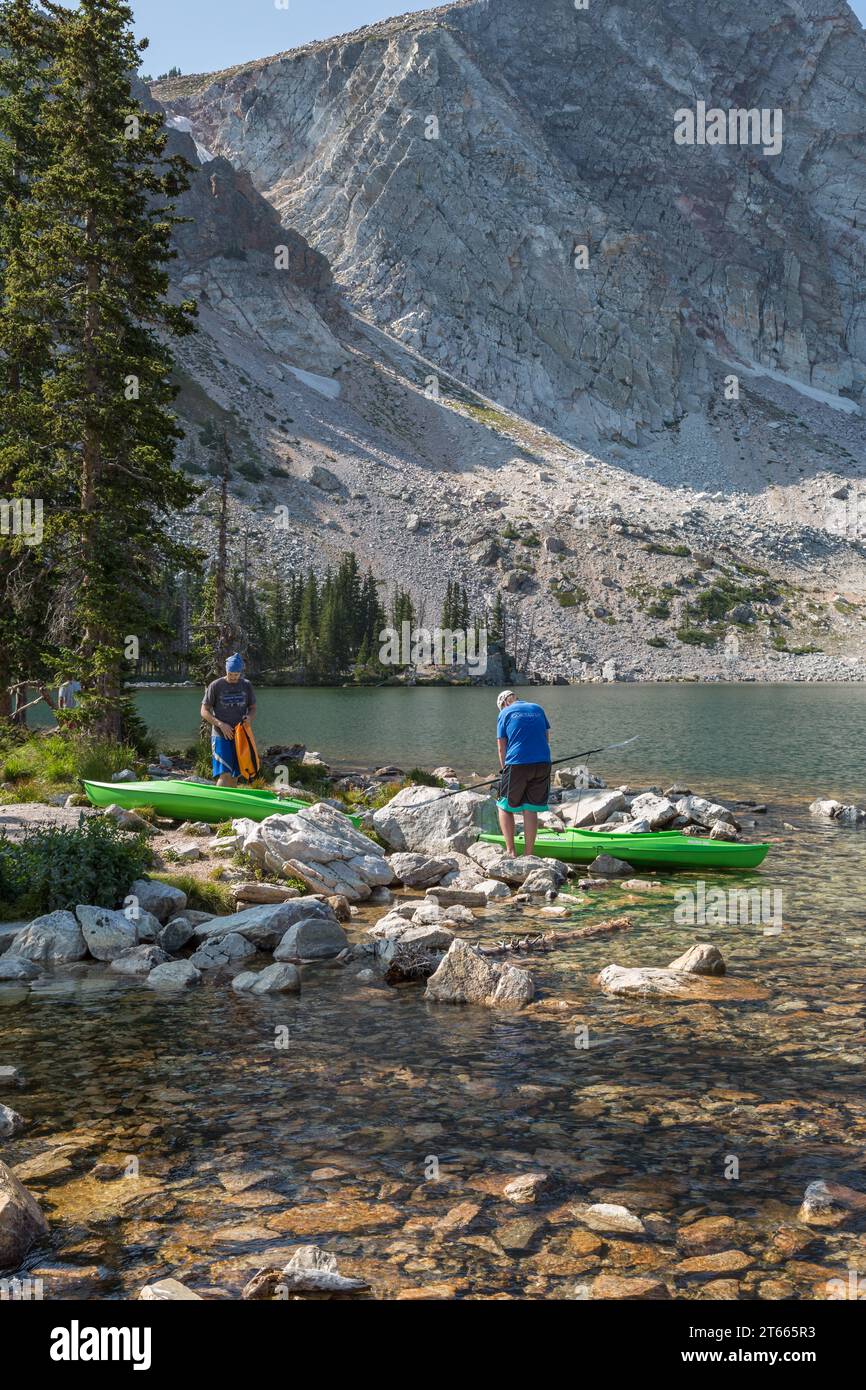 Two young men prepare for kayaking along the rock shoreline of Lake ...