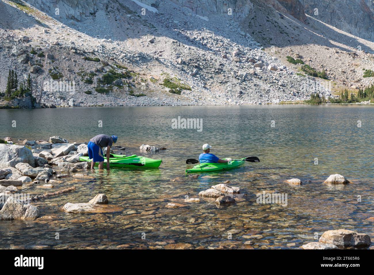Two young men prepare for kayaking along the rock shoreline of Lake ...