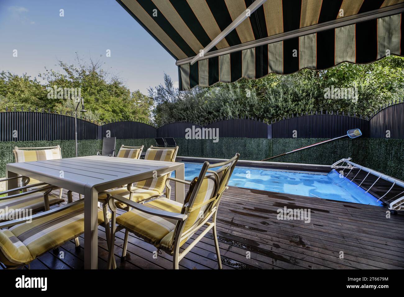 Terrace with covered pool of a single-family home with acacia wood ...