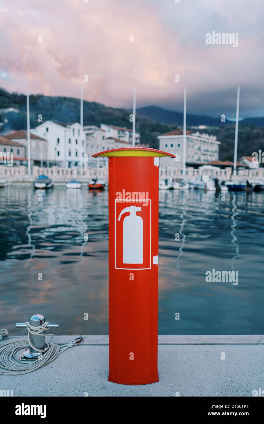 Red fire stand with a fire extinguisher inside stands on a yacht pier ...