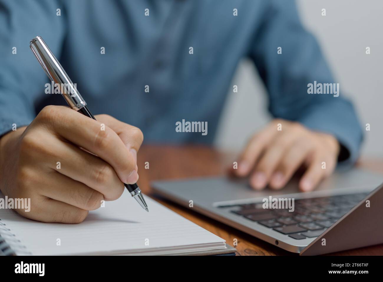 Man Writing with Pen on Notebook and laptop on desk. Business Success ...