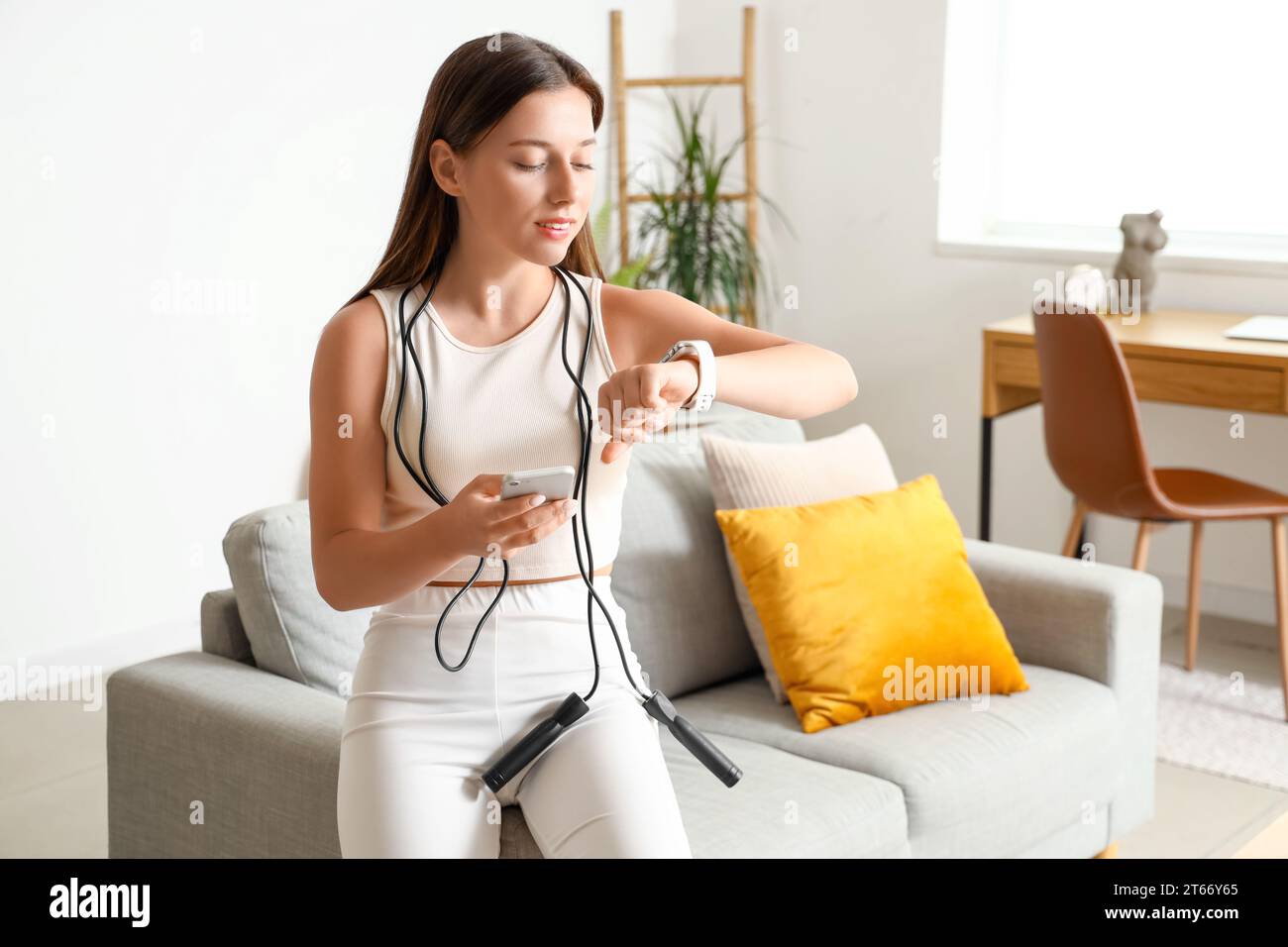 Sporty young woman with jumping rope and fitness tracker at home Stock ...