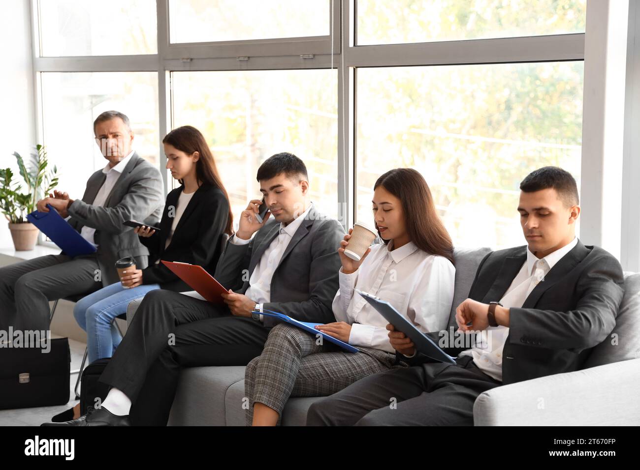 Business people waiting for their turn in office hall Stock Photo - Alamy