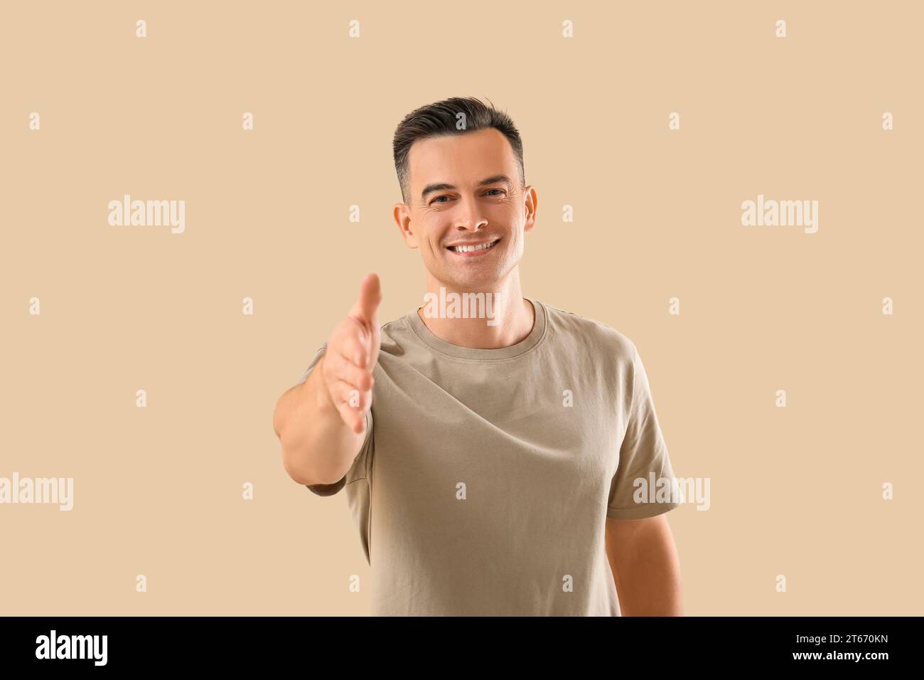 Young man reaching out for handshake on beige background Stock Photo ...