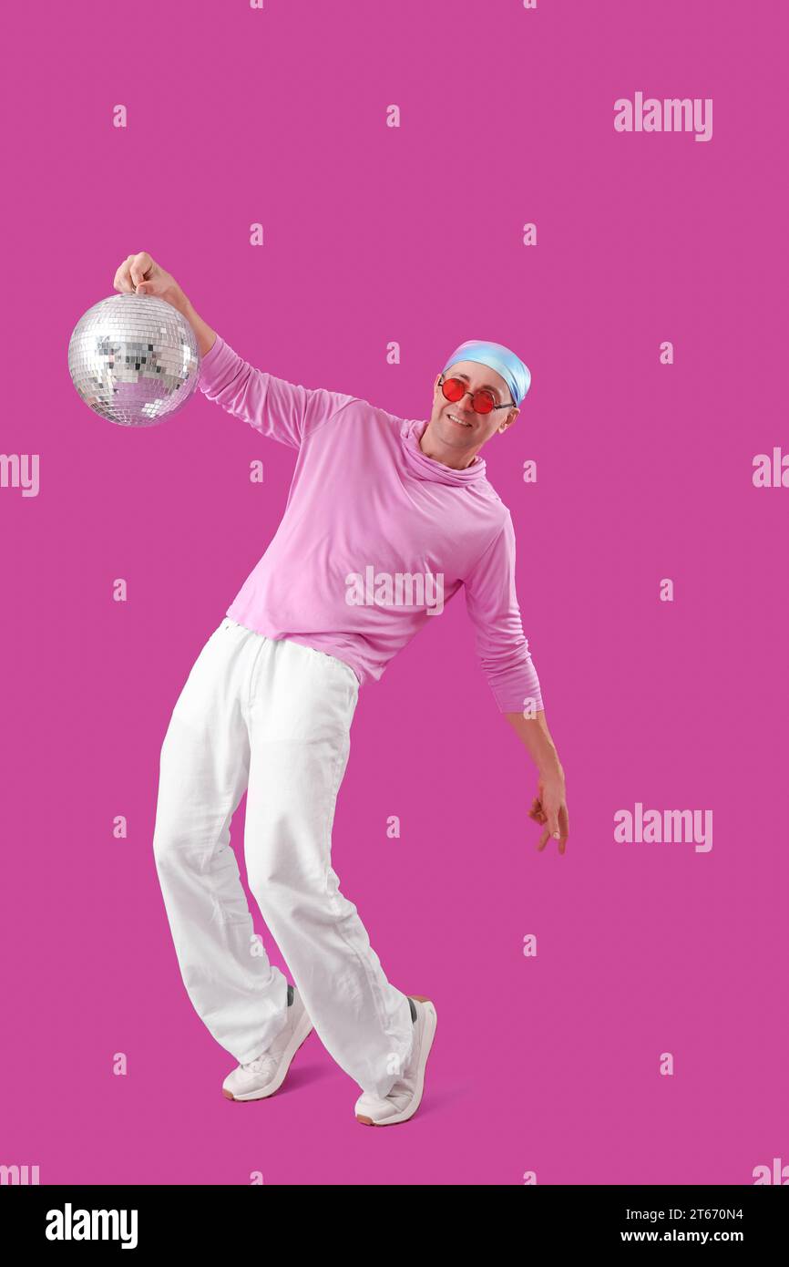 Cool mature man with disco ball dancing on purple background Stock ...