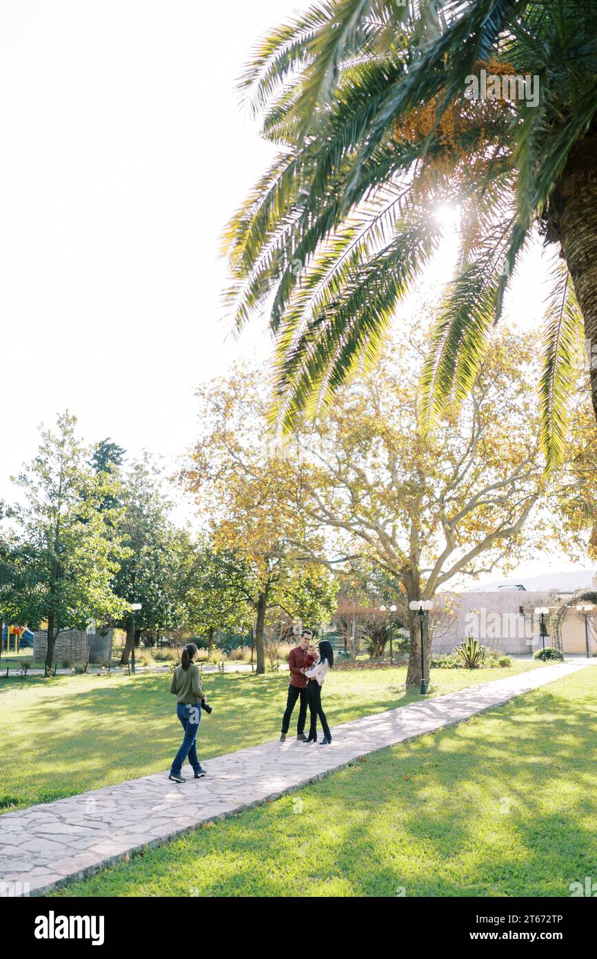 Girl-photographer walks along the path in the park to parents with a ...