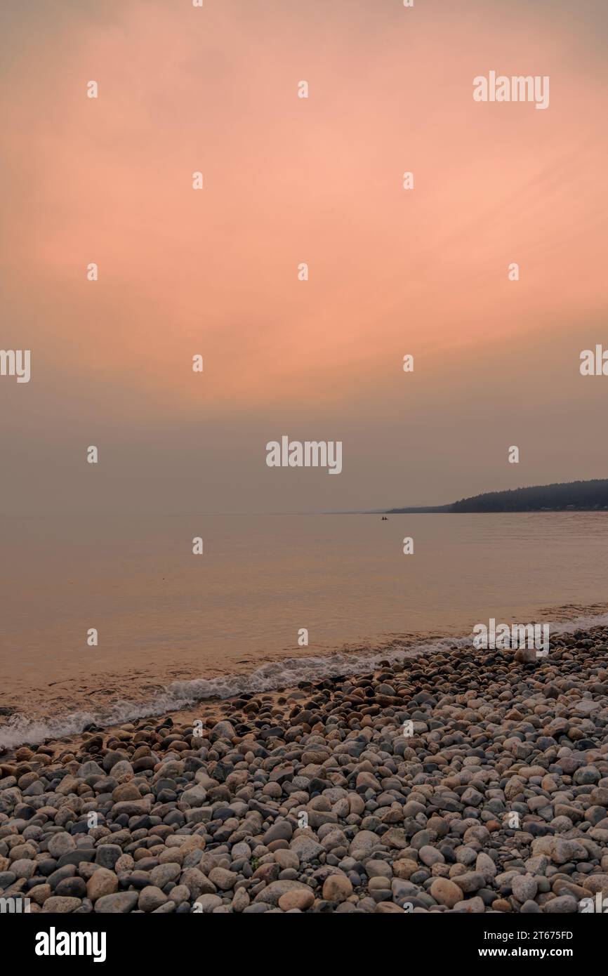 Smoky sunset on the Sunshine Coast in Canada, with the sun hidden by ...