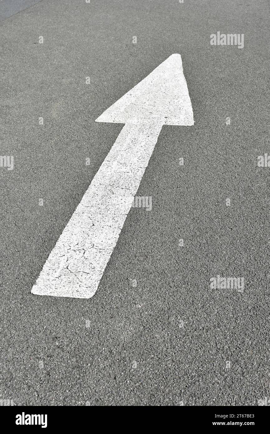 White painted arrow road or street marking sign showing the way forward ...