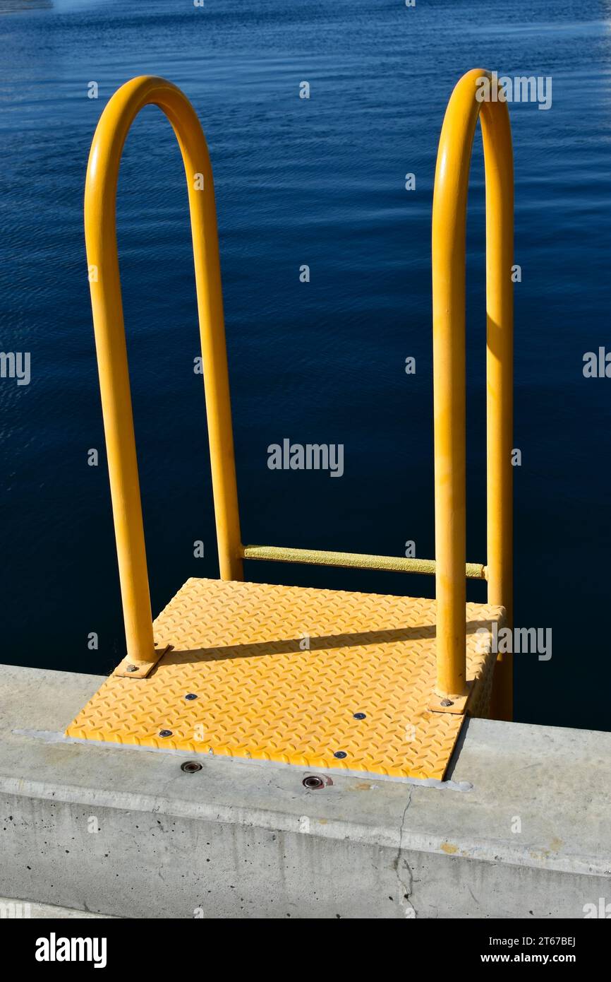 Yellow safety stairs leading into water at an outdoor swimming pool ...