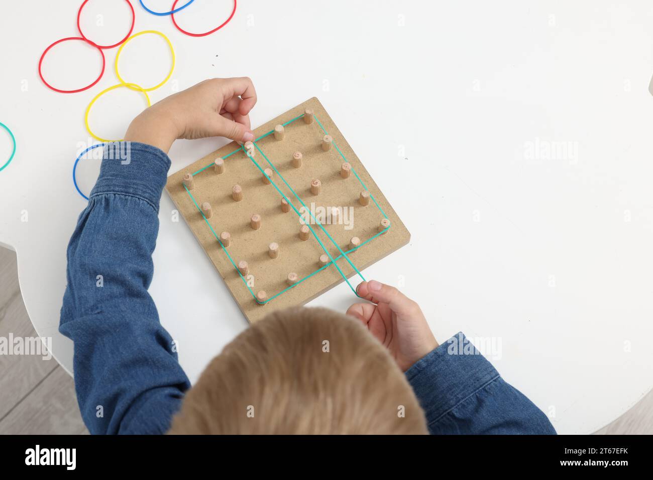Motor skills development. Boy playing with geoboard and rubber bands at ...