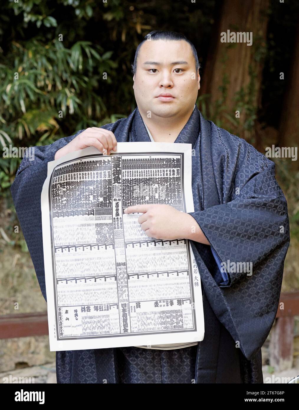 Rank-and-file wrestler Kitanowaka holds up the banzuke for the upcoming ...