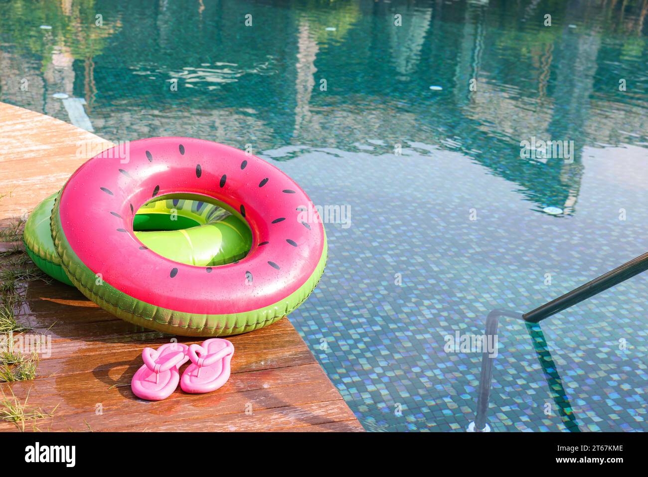 Inflatable rings and flip flops on wooden deck near swimming pool ...