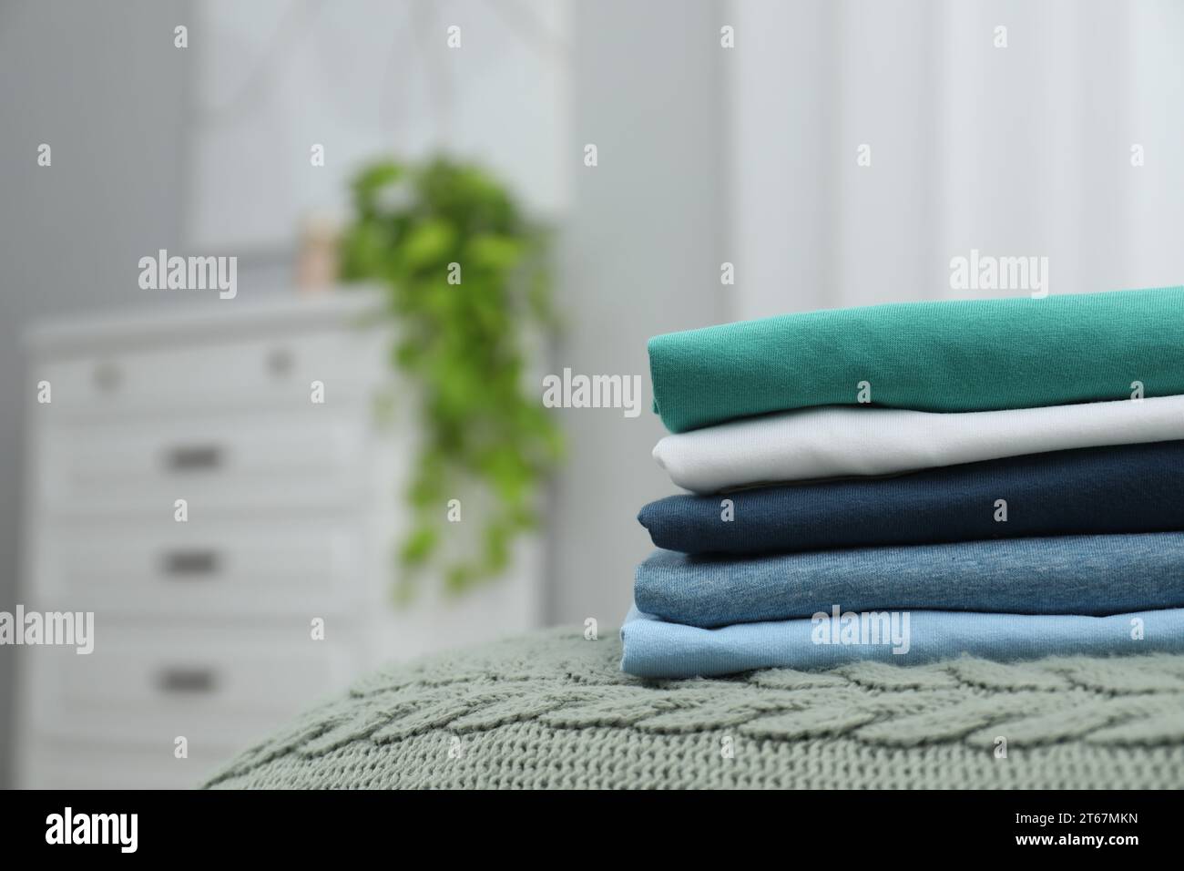 Sorting and organizing. Stack of different folded clothes on bed ...