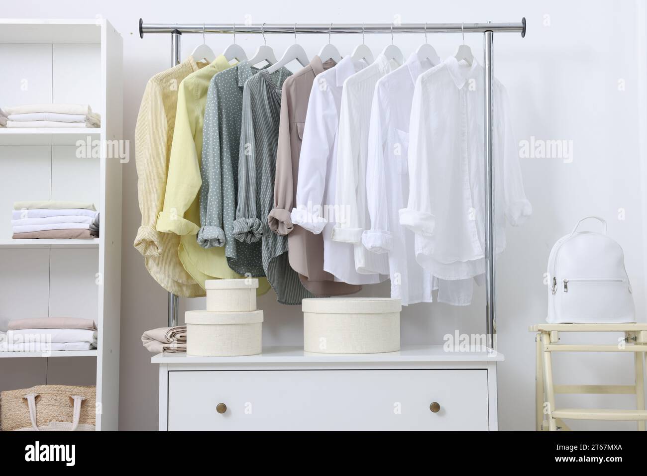 Wardrobe organization. Rack with different stylish clothes, chest of ...