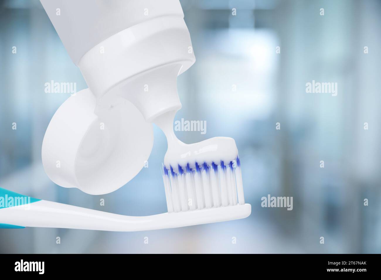 Squeezing toothpaste onto toothbrush against blurred background Stock ...