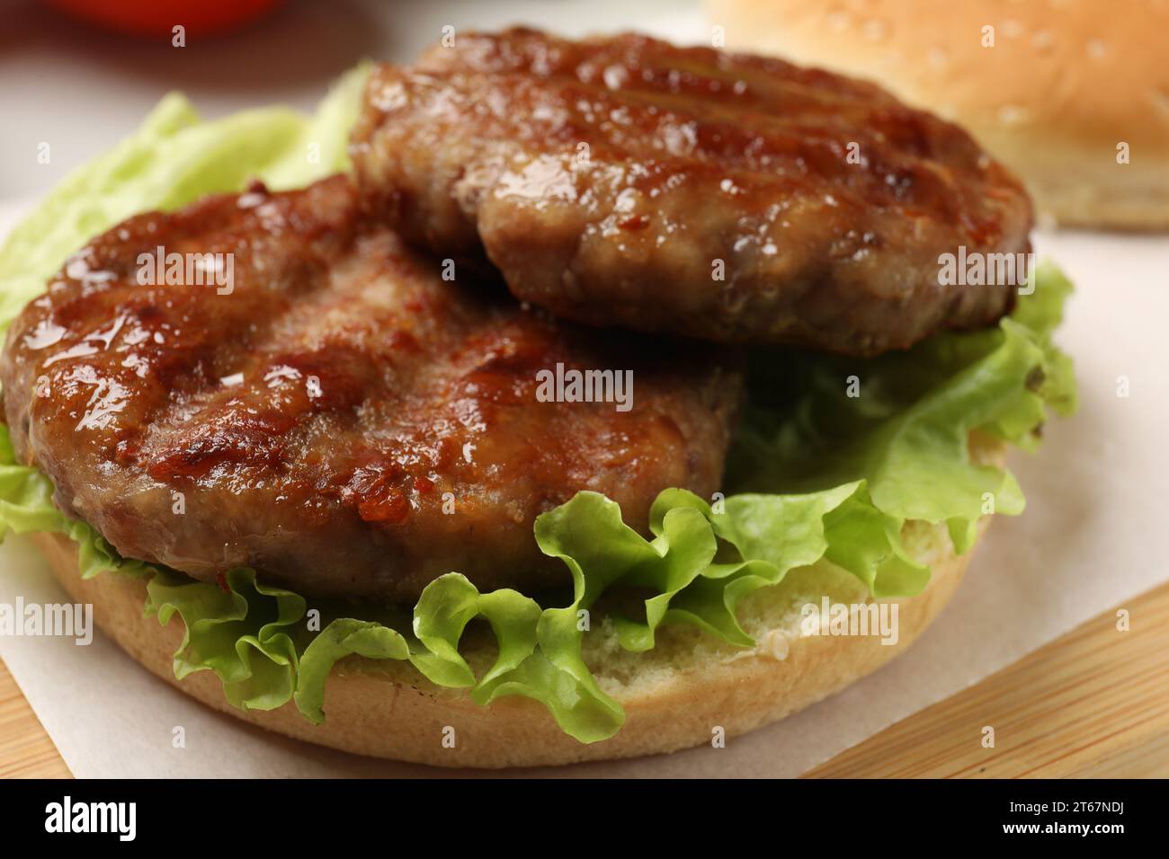 Delicious fried patties, lettuce and bun on board, closeup. Making ...