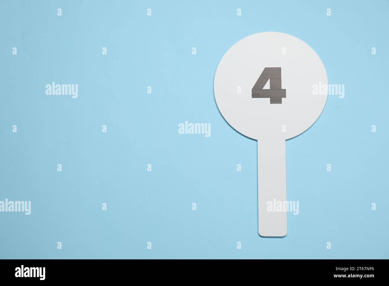 Auction paddle with number 4 on light blue background, top view. Space ...