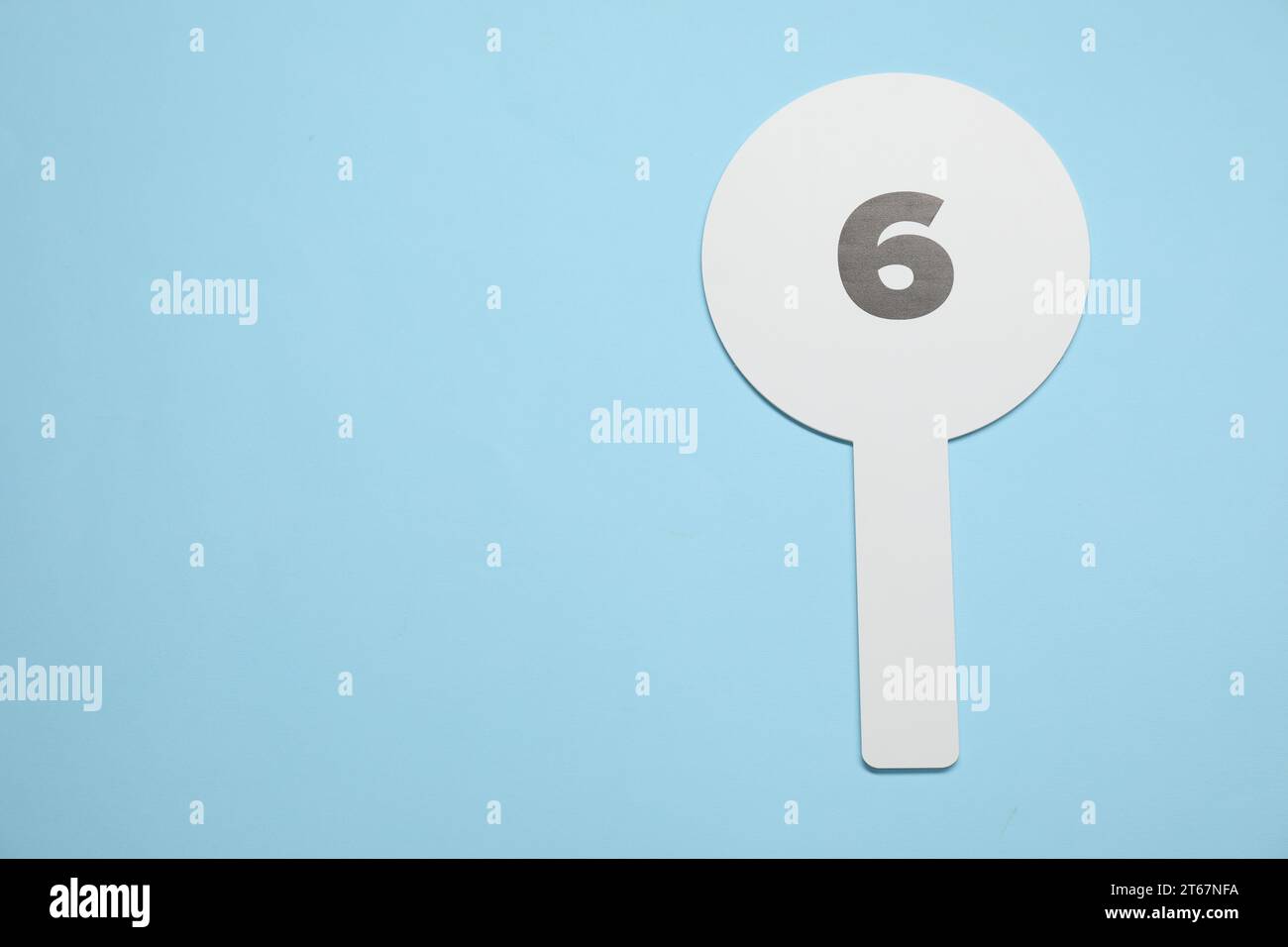 Auction paddle with number 6 on light blue background, top view. Space ...