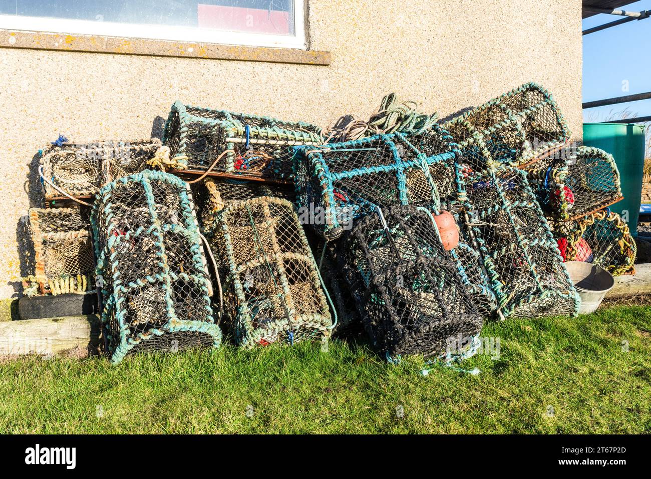 Traditional lobster pots or crab pots stacked up on the quayside in the ...