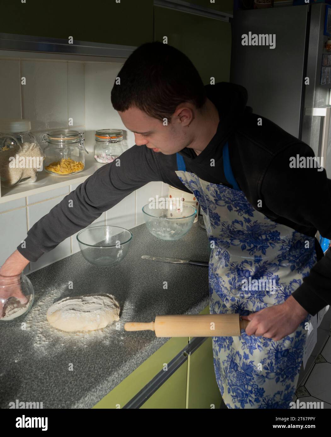 Teenage boy making bread and cutting the bread dough with a palette ...