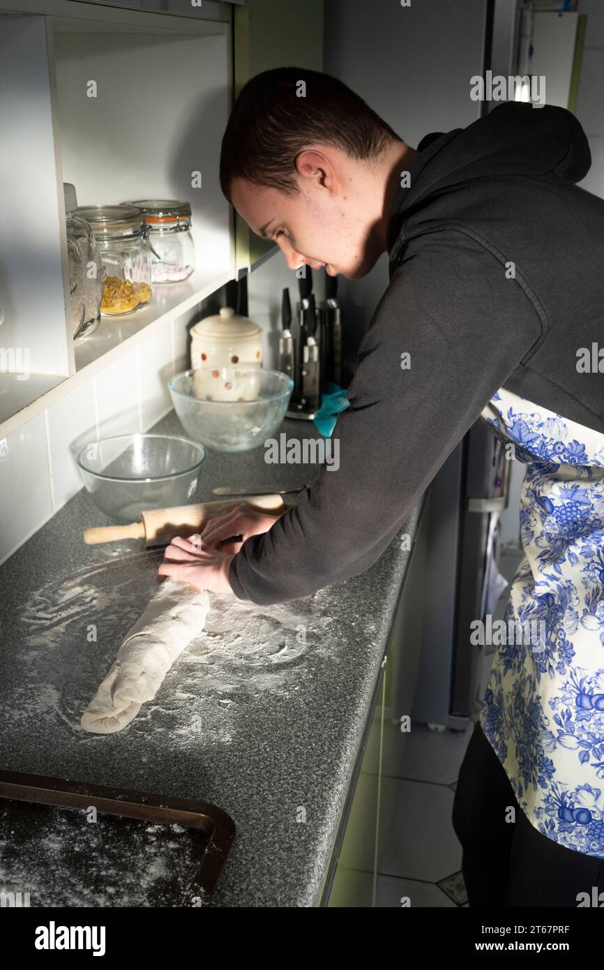 Teenage boy making bread in the kitchen at home wearing an apron Stock ...