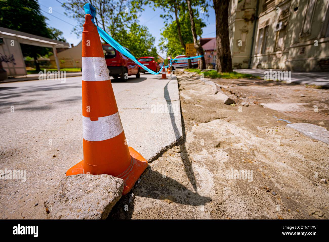 Orange traffic cone with white fluorescent stripes is on the road for ...
