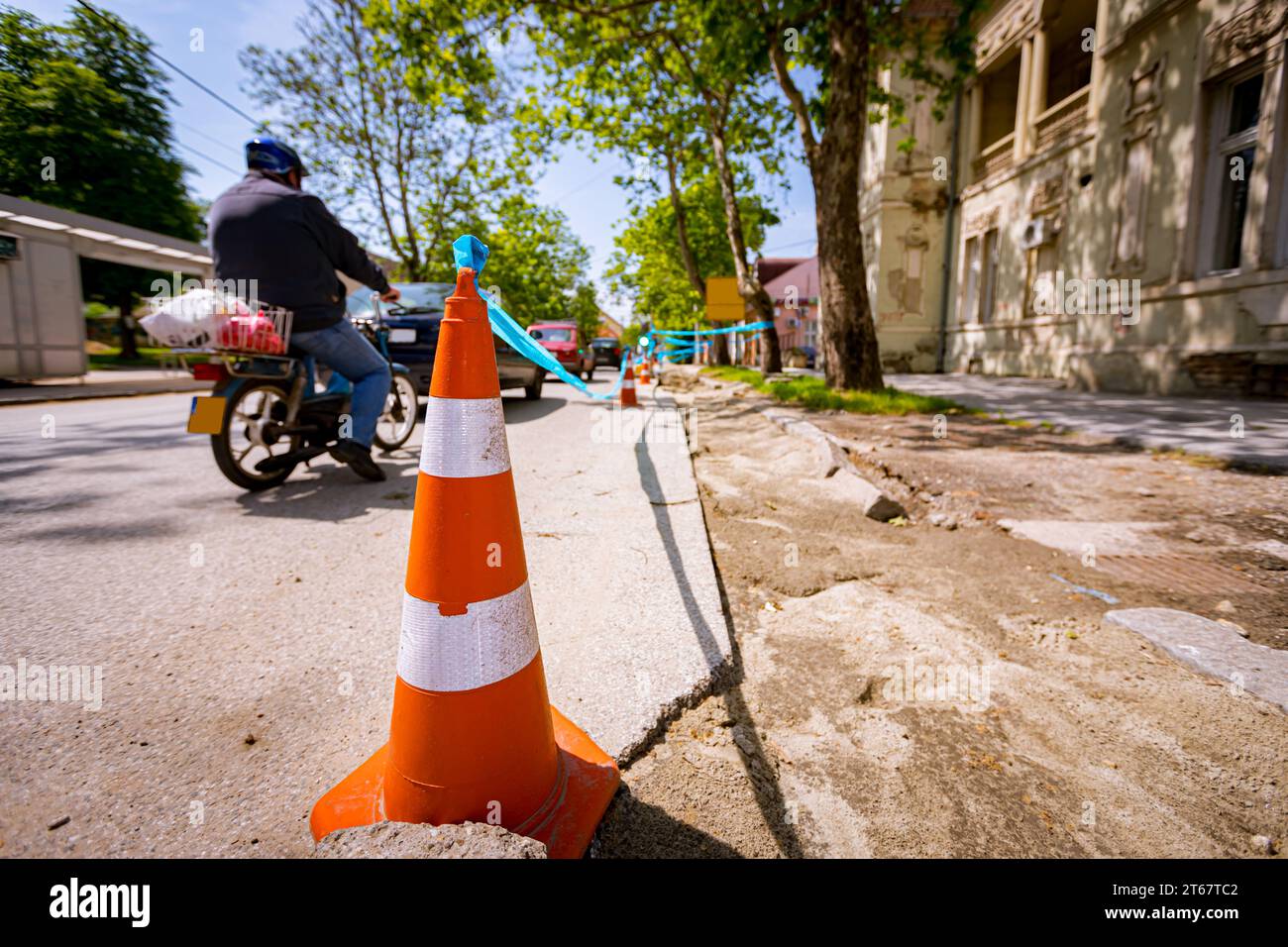 Orange traffic cone with white fluorescent stripes is on the road for ...