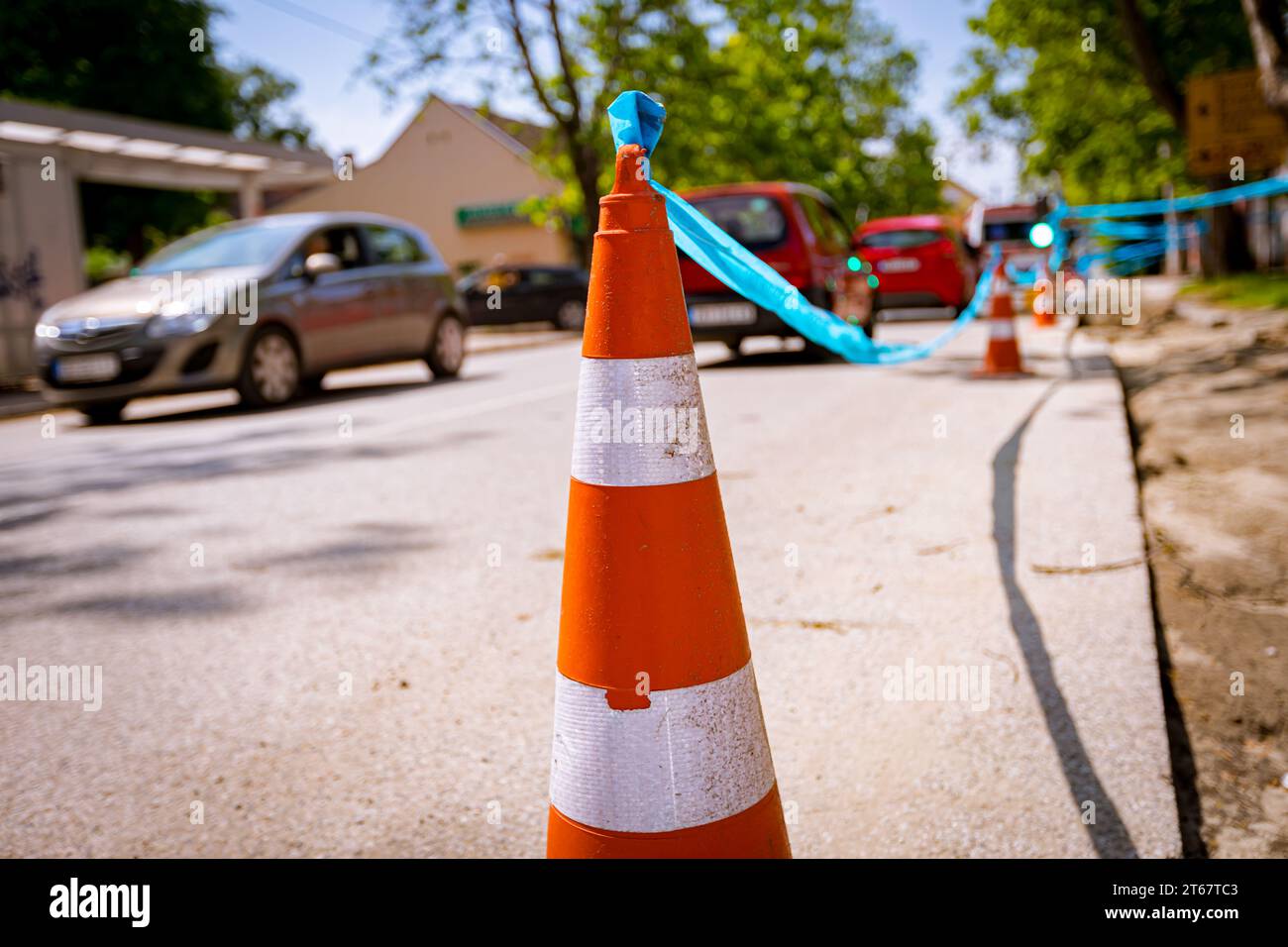 Orange traffic cone with white fluorescent stripes is on the road for ...