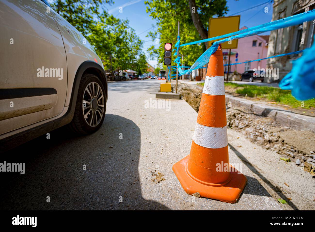 Orange traffic cone with white fluorescent stripes is on the road for ...