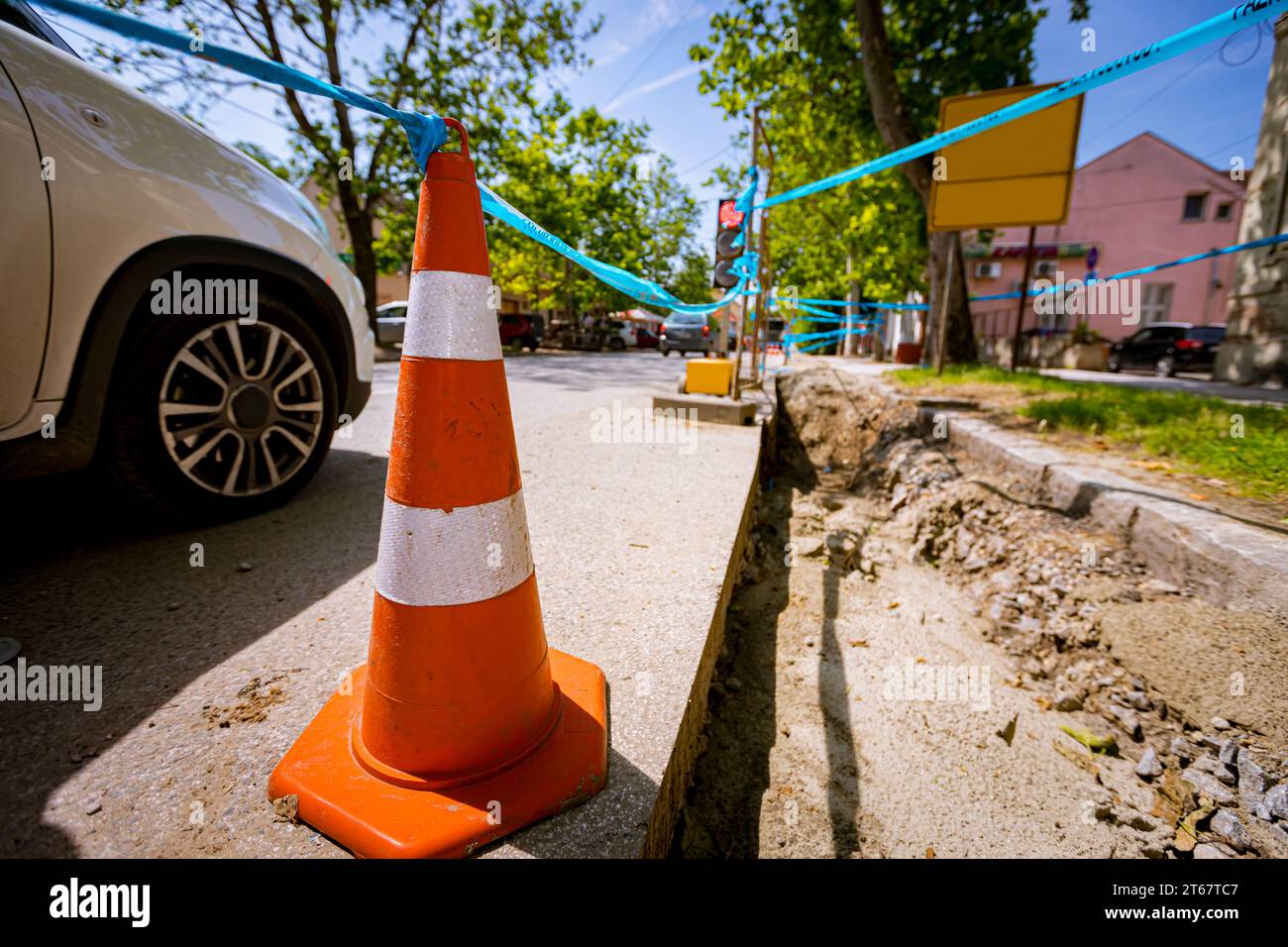 Orange traffic cone with white fluorescent stripes is on the road for ...
