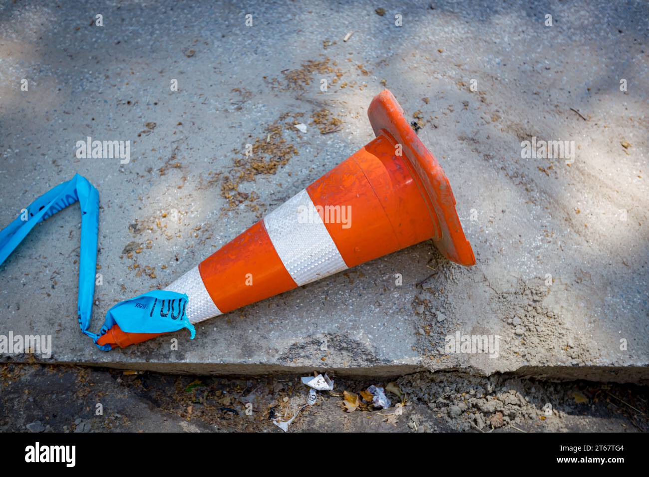 Fallen orange traffic cone with white fluorescent stripes is on the ...