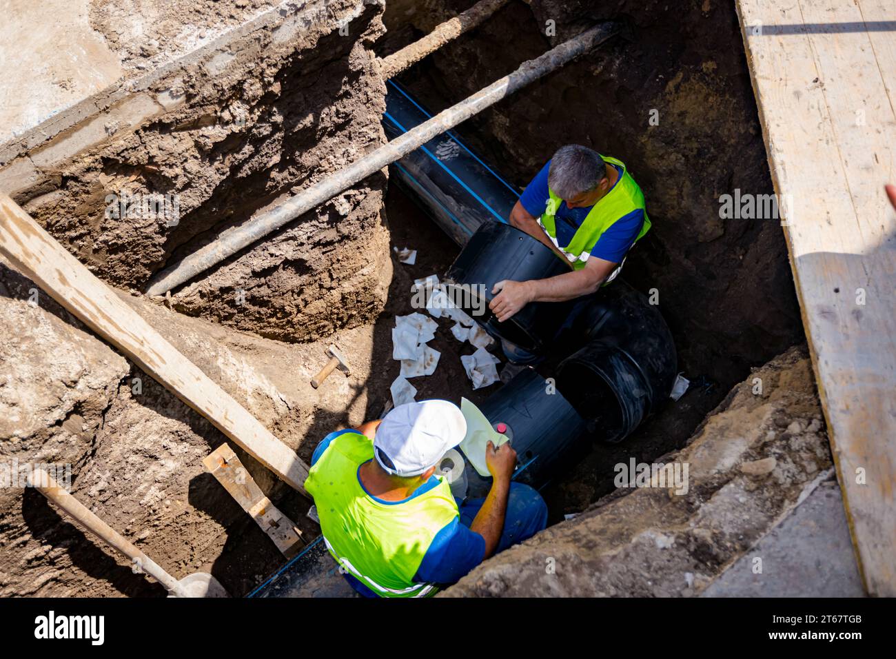 Above view on workers, riggers in trench as they assembly a new plastic ...