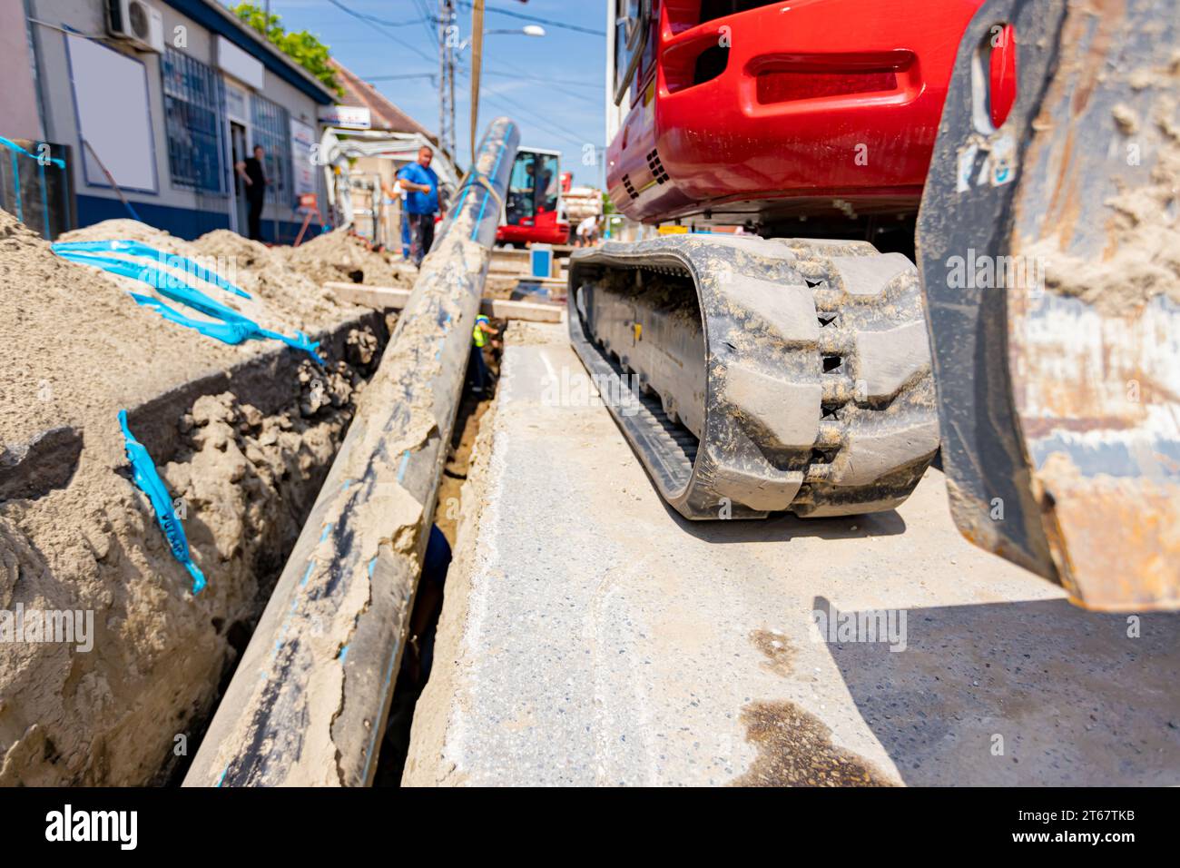 Small excavator with rubber crawler is standing next to the trench with ...