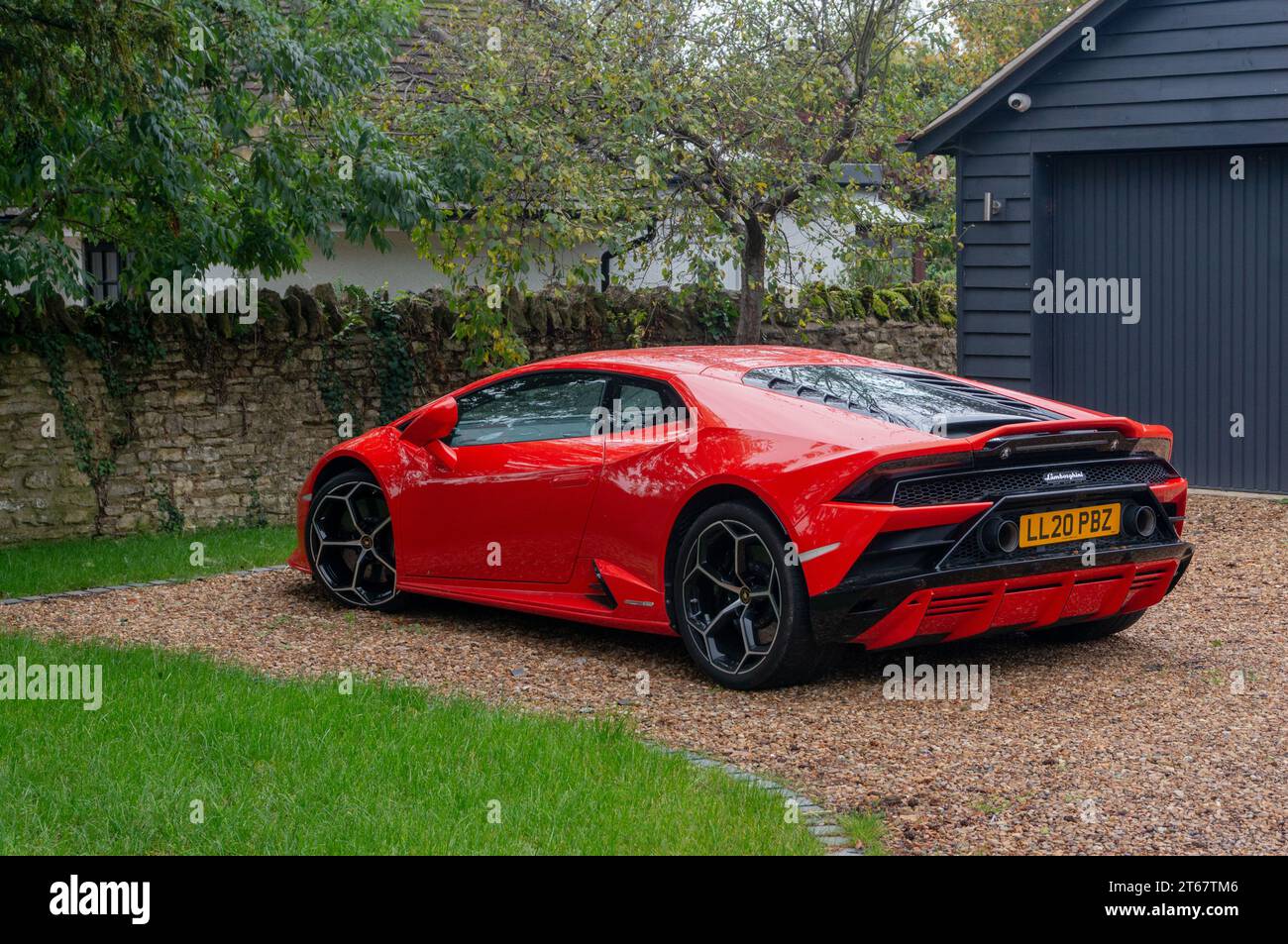 Red Lamborghini sports car parked in the drive of a house in the ...