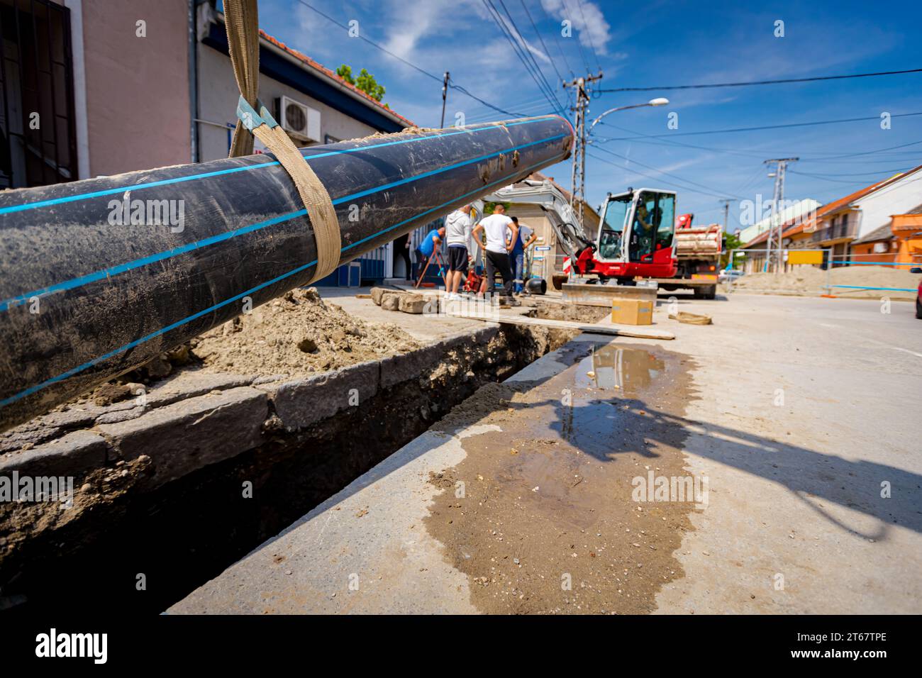 Small excavator with rubber crawler is standing next to the trench with ...