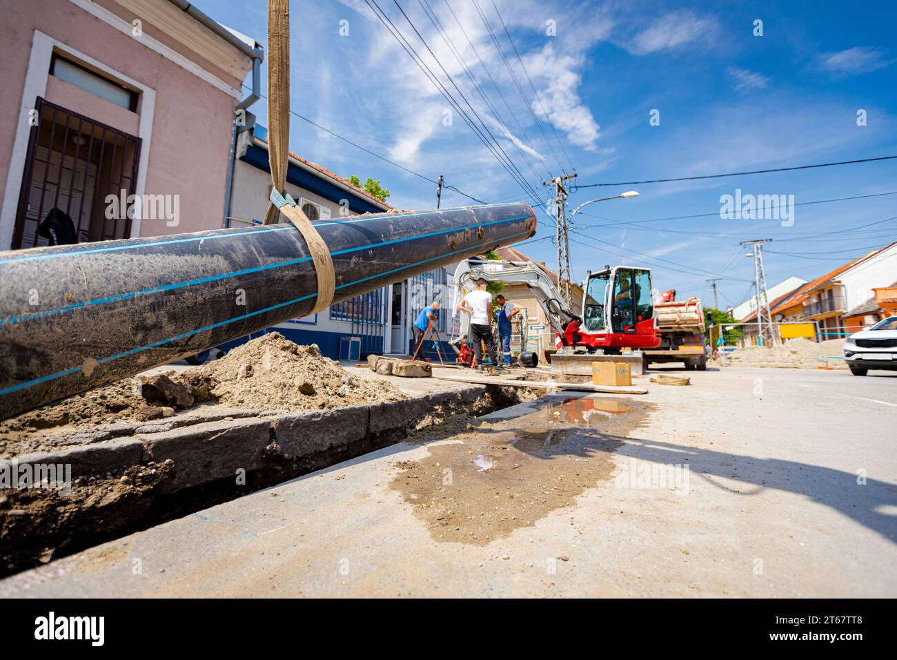 Small excavator with rubber crawler is standing next to the trench with ...
