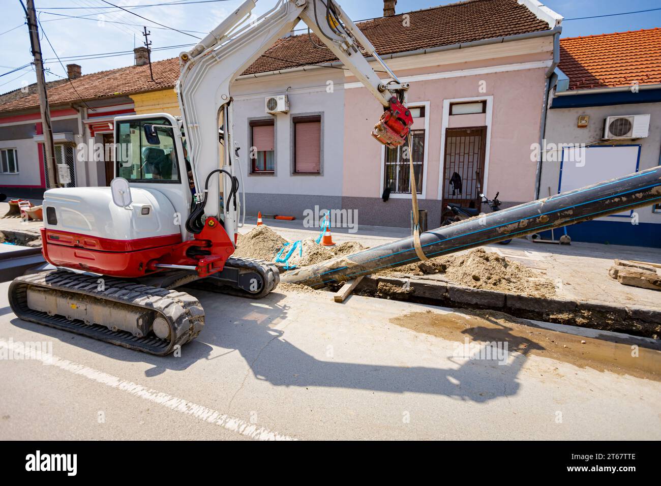 Small excavator with rubber crawler is standing next to the trench with ...