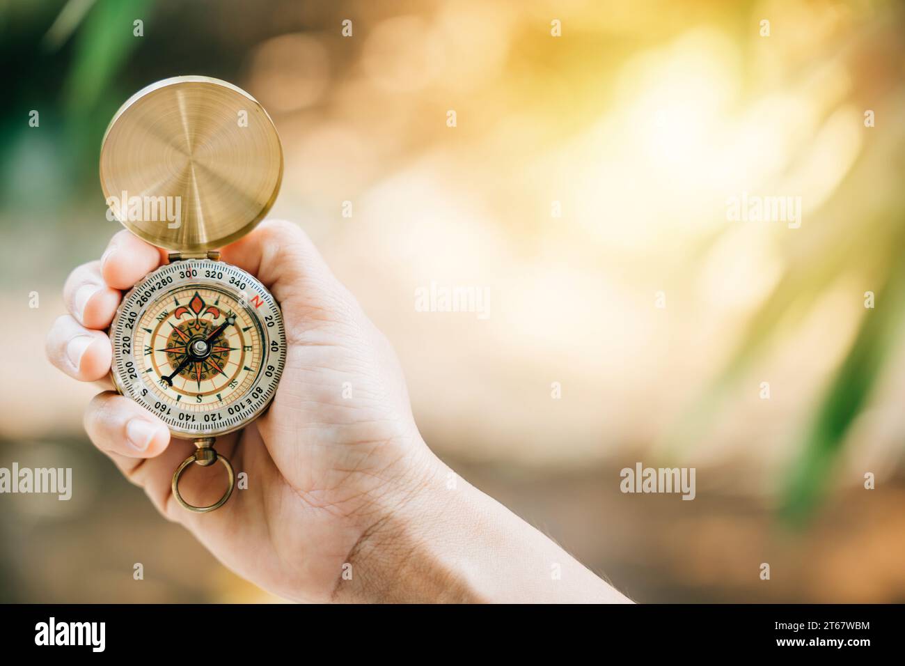 With a hand holding a compass in a natural forest setting find your ...