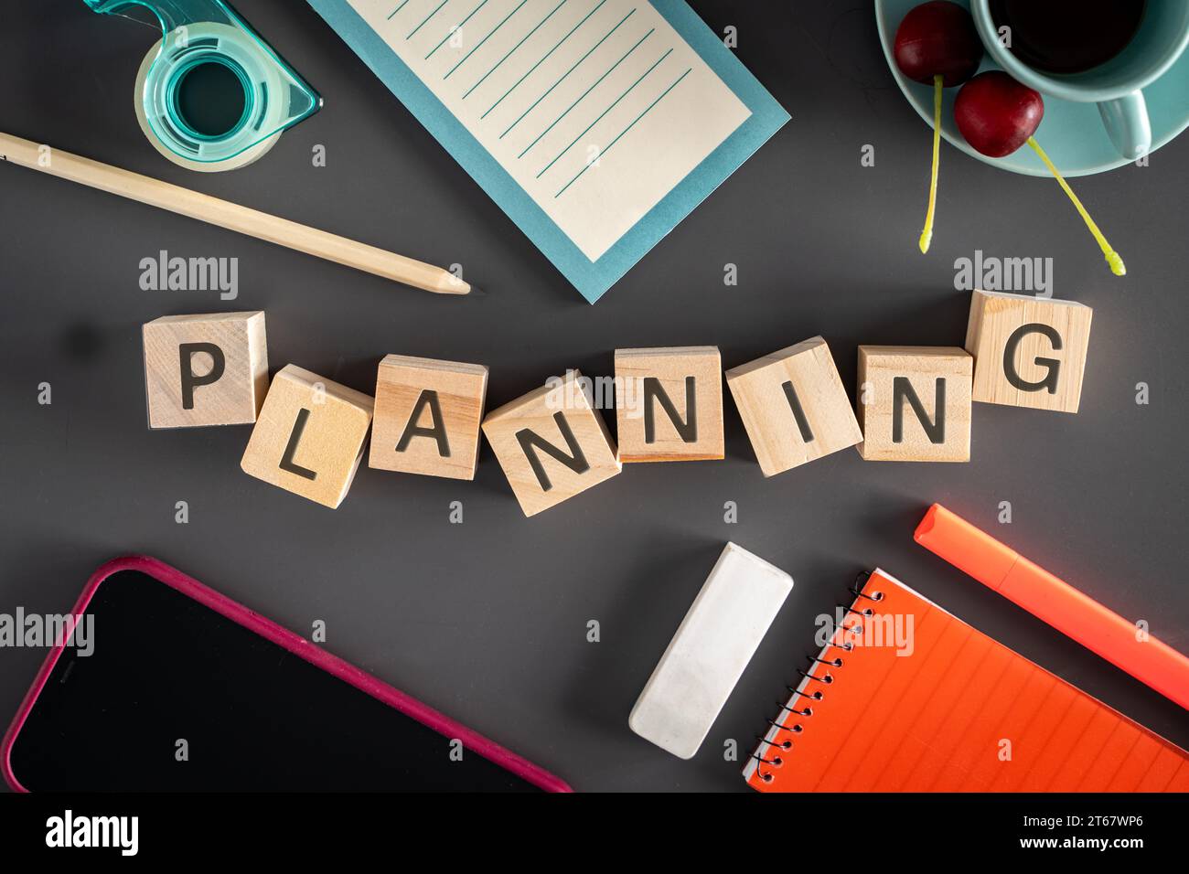 Flat lay of a well-organized desk with wooden blocks spelling 'PLANNING ...